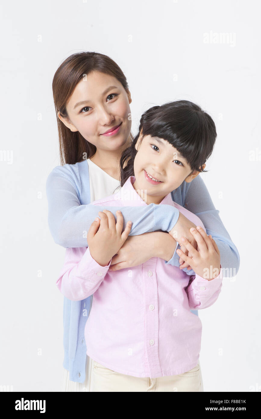 Mother hugging her daughter from behind both staring forward with a smile Stock Photo - Alamy