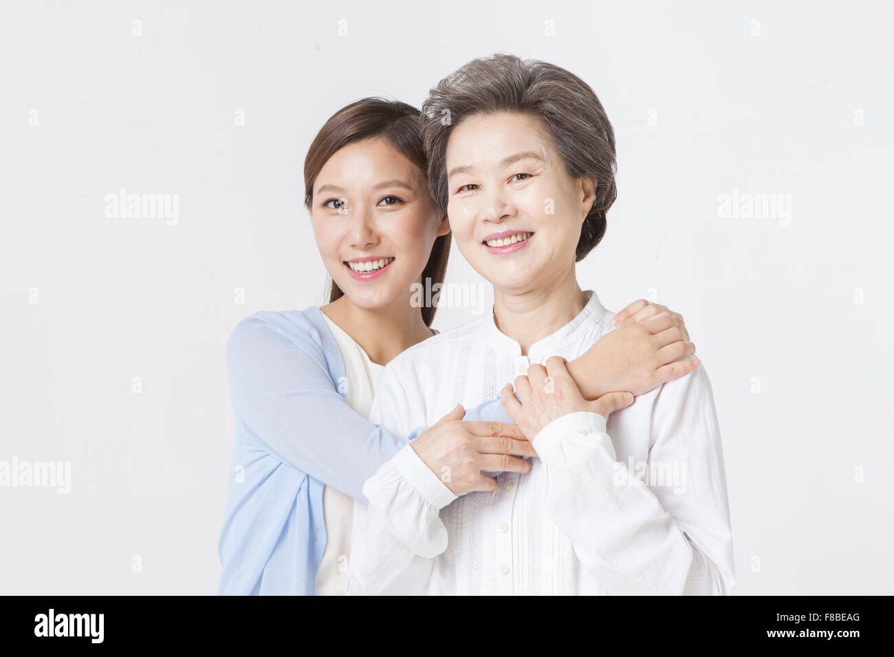 Daughter hugging her mother both staring forward with a smile Stock ...