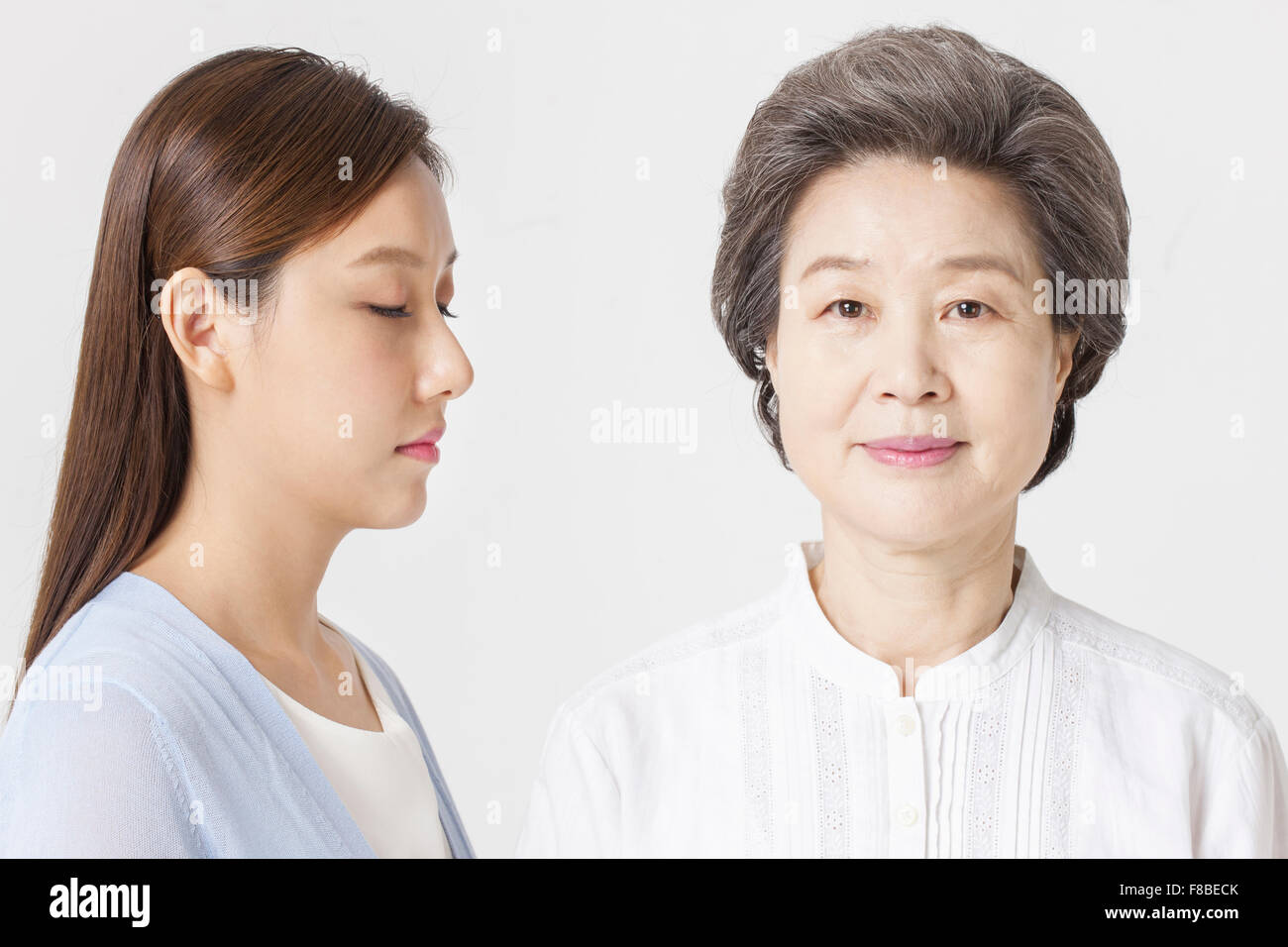 Daughter facing her mother with her eyes closed and mother staring ...