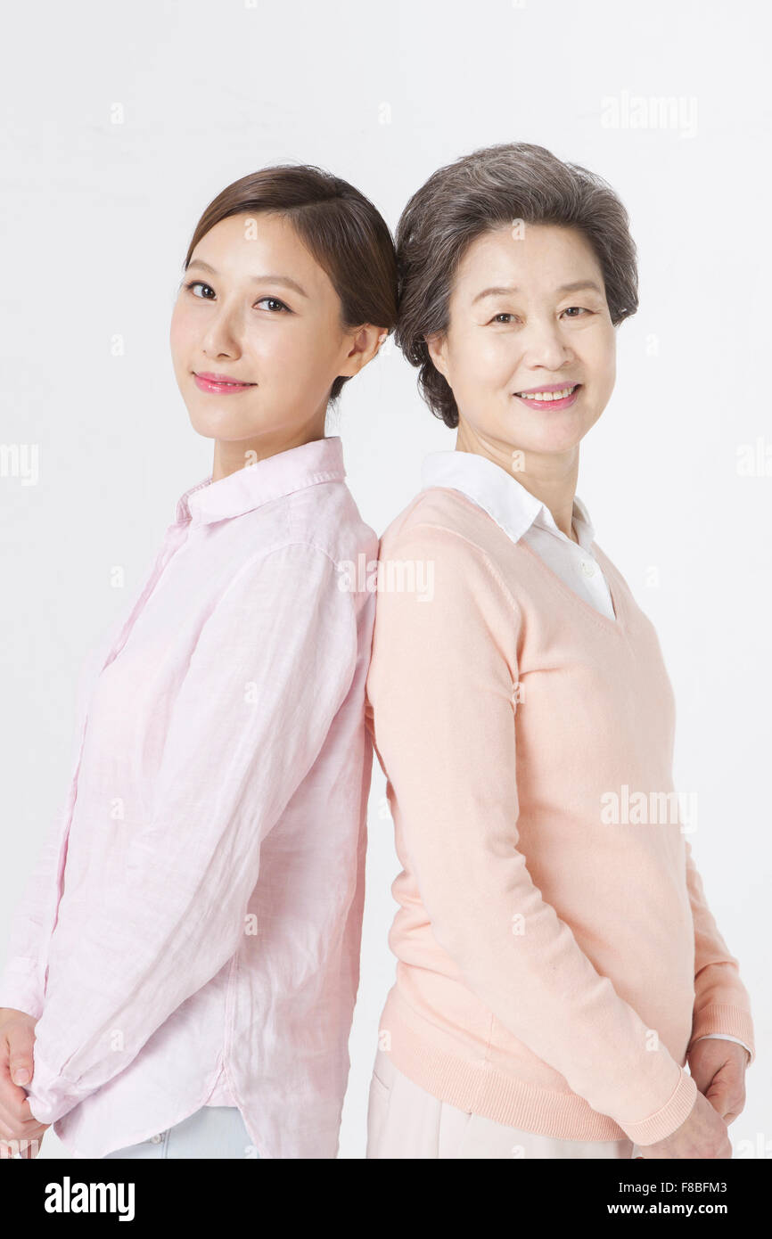 Mother and daughter standing back to back each other both staring ...