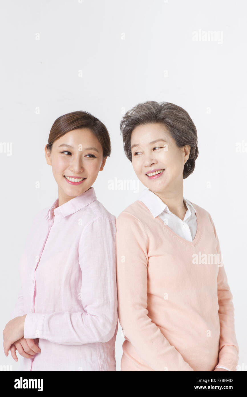 Mother And Daughter Standing Back To Back Each Other And Looking At