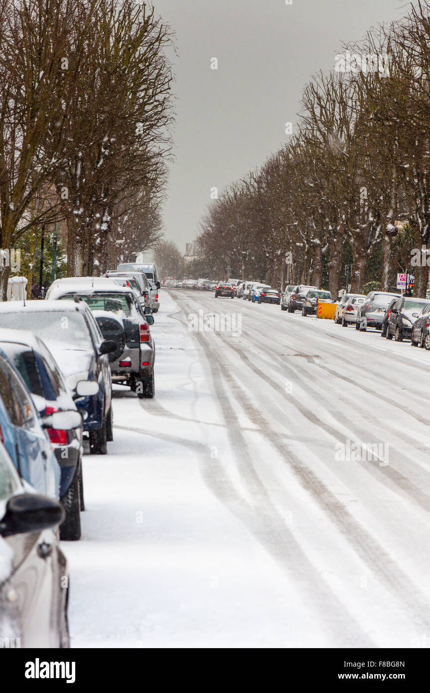 Road lined with parked cars after a light snowfall. Tracks through the ...