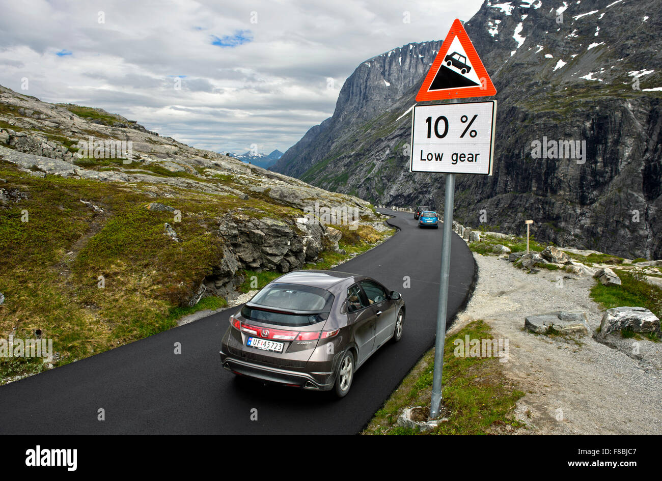 Cars by a warning sign in front of a steep slope, on the mountain road ...