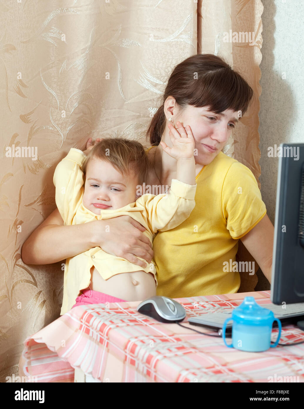 Woman with crying baby working with computer at home Stock Photo - Alamy