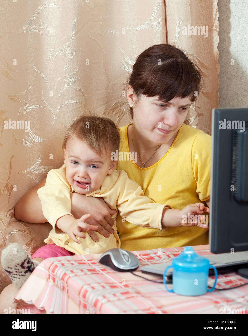 Woman with crying baby working with computer at home Stock Photo - Alamy
