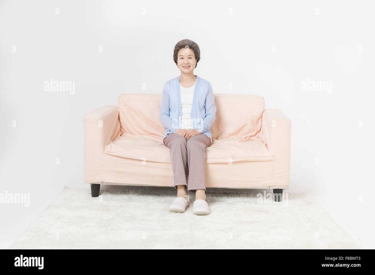 Senior woman sitting on a couch staring forward with a smile Stock ...