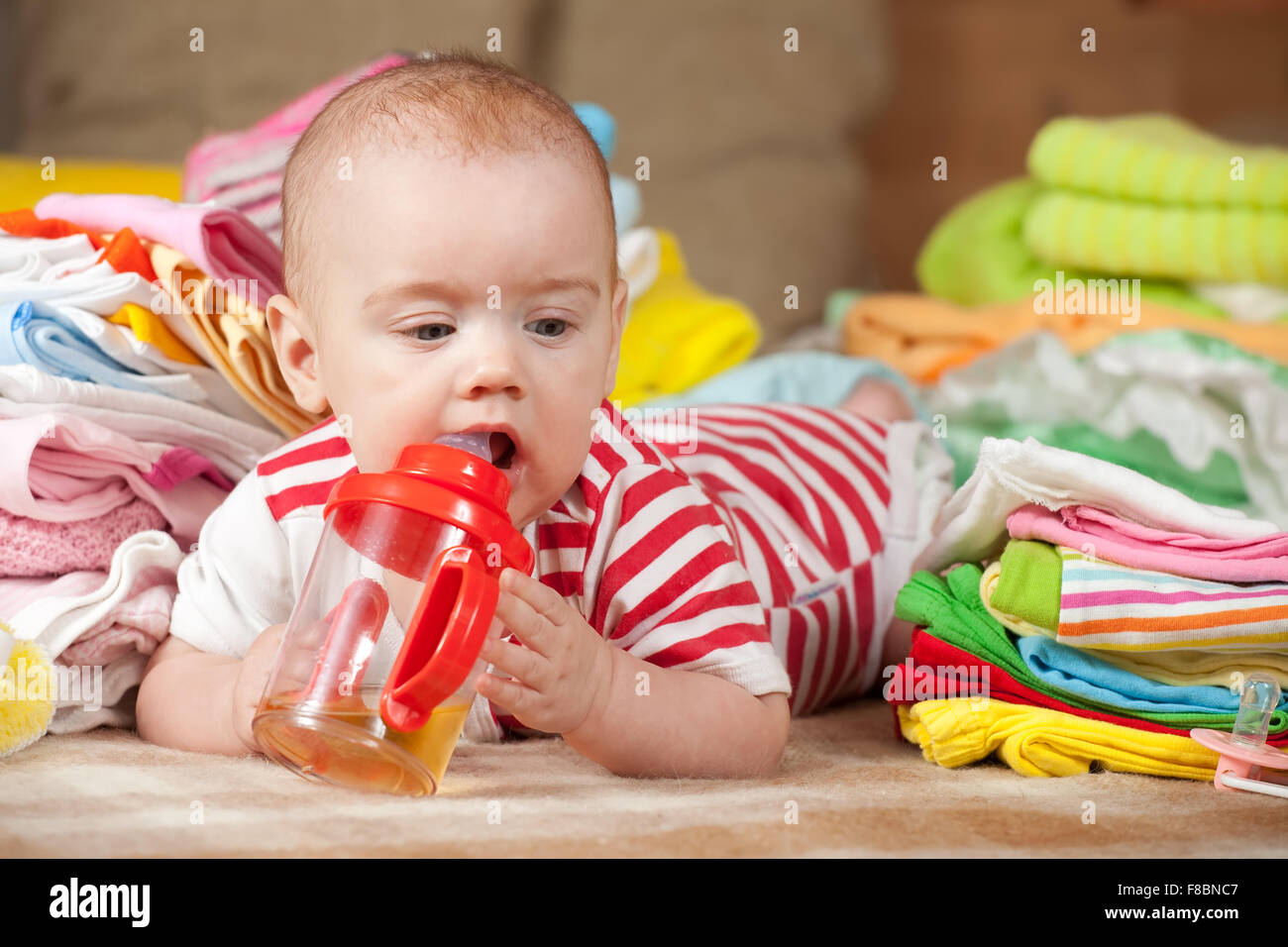 Happy baby girl with heap of baby's things Stock Photo - Alamy