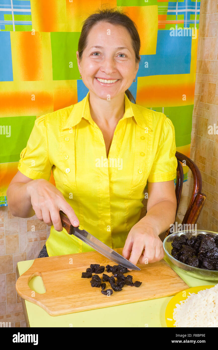 Mature woman slicing prune on cutting board in her kitchen Stock Photo ...