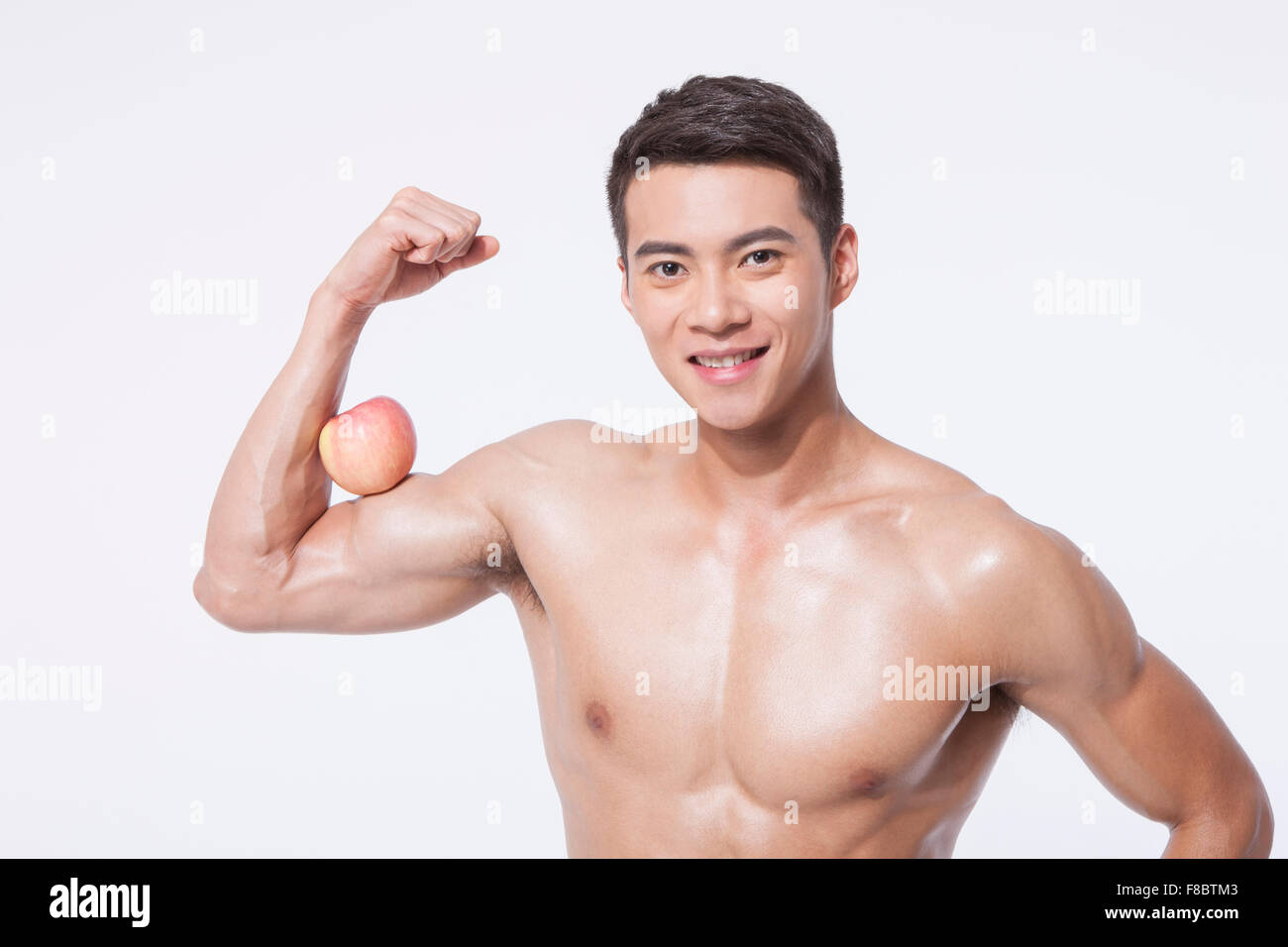 Muscular man with his hand up and showing his muscles with an apple ...