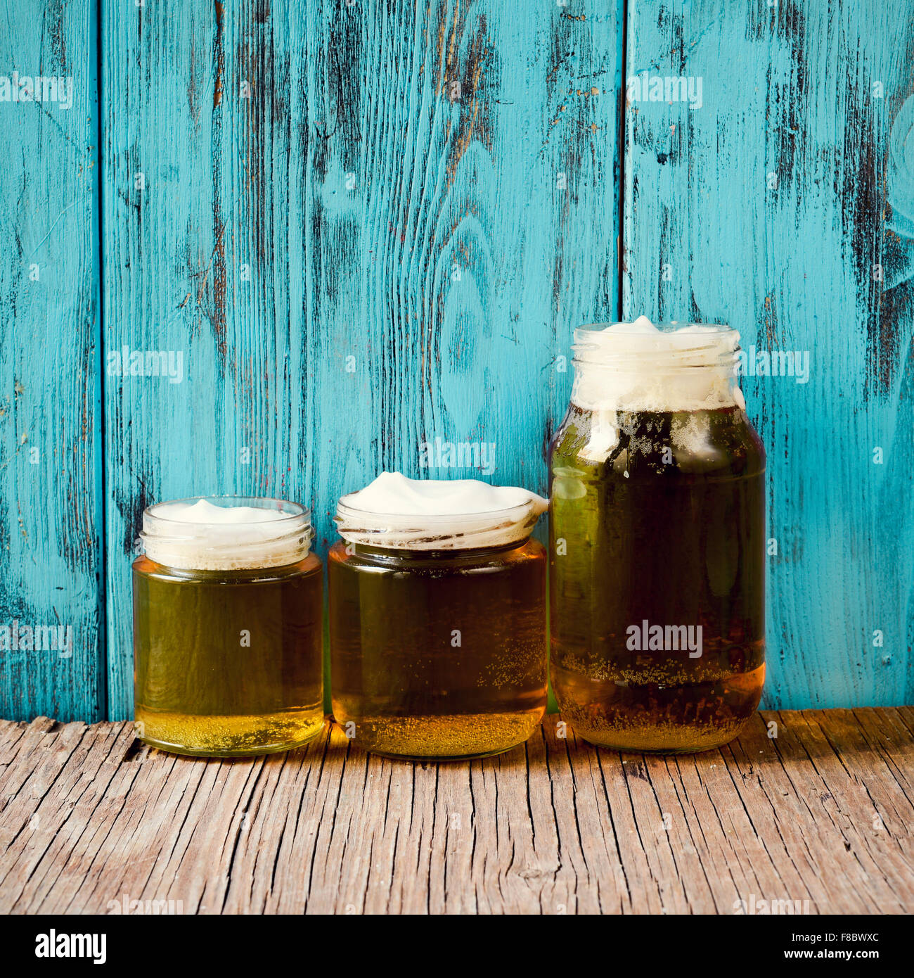 refreshing beer served in some glass jars on a rustic wooden surface ...