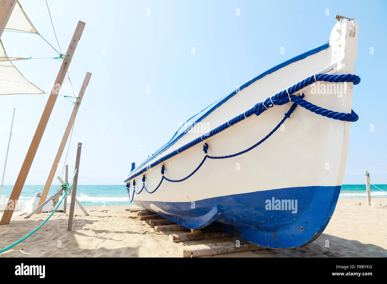 White wooden boat lays on sandy beach, Mediterranean sea coast, Spain ...