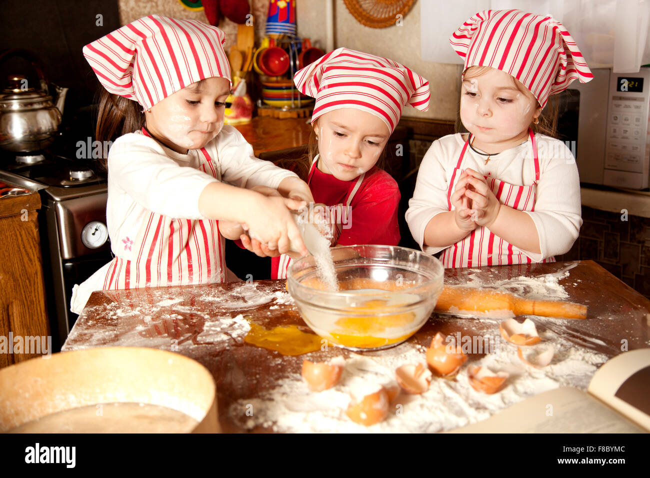 Three little chefs enjoying in the kitchen making big mess. Litt Stock ...