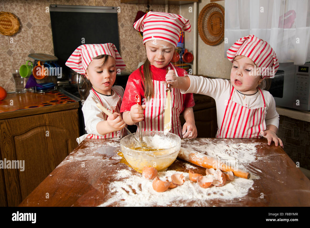 Three little chefs enjoying in the kitchen making big mess. Litt Stock ...
