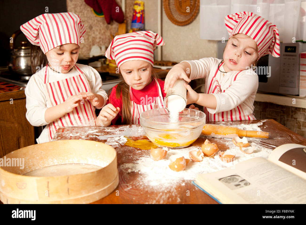 Three little chefs enjoying in the kitchen making big mess. Litt Stock ...