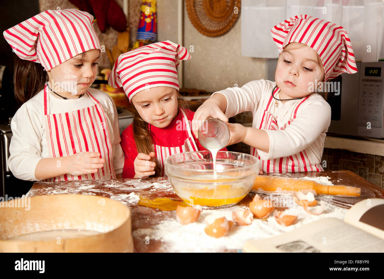 Three little chefs enjoying in the kitchen making big mess. Litt Stock ...