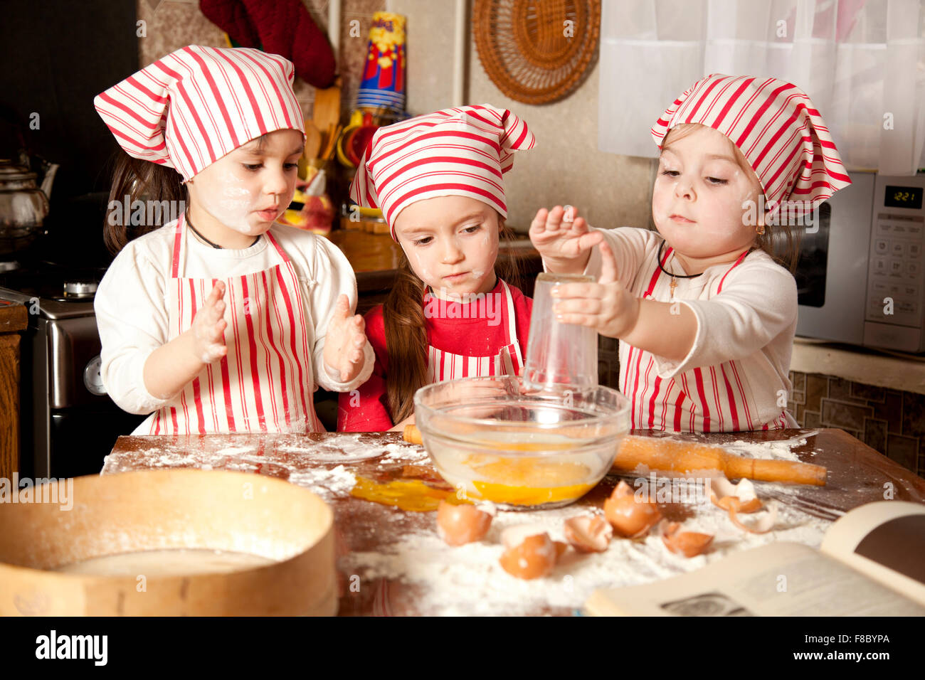 Three little chefs enjoying in the kitchen making big mess. Litt Stock ...