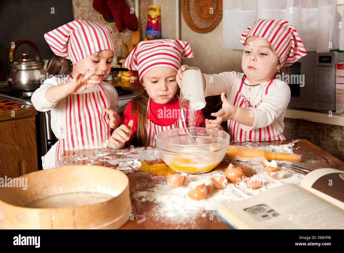 Three little chefs enjoying in the kitchen making big mess. Litt Stock ...