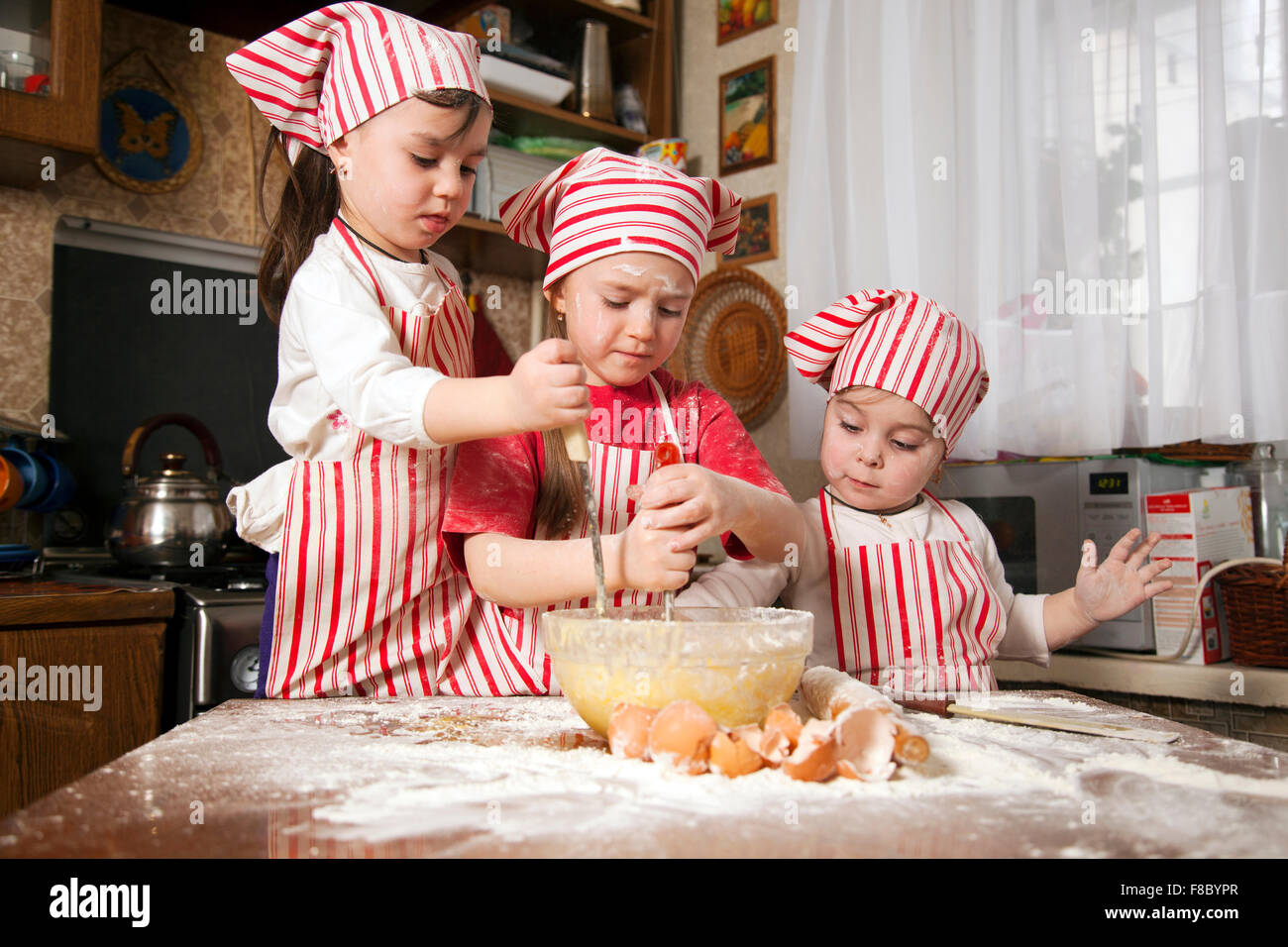Three little chefs enjoying in the kitchen making big mess. Litt Stock ...