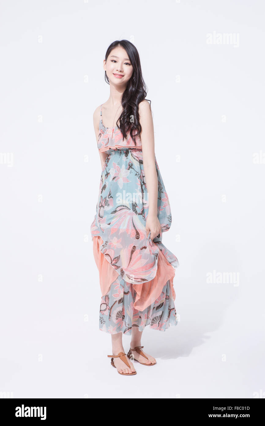 Woman with long hair in long dress and sandals standing and holding her ...