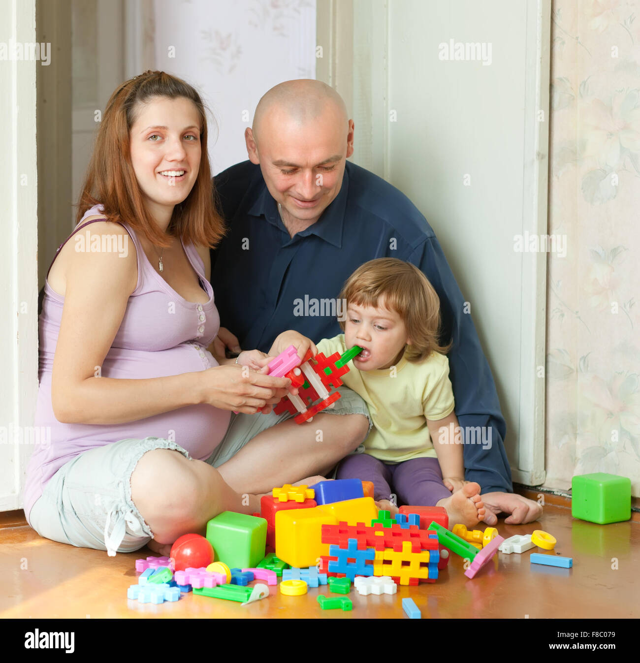 Happy parents and child plays with plastic toys in home Stock Photo - Alamy