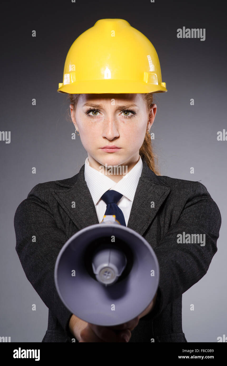 Female engineer with helmet and loudspeaker isolated on gray Stock ...