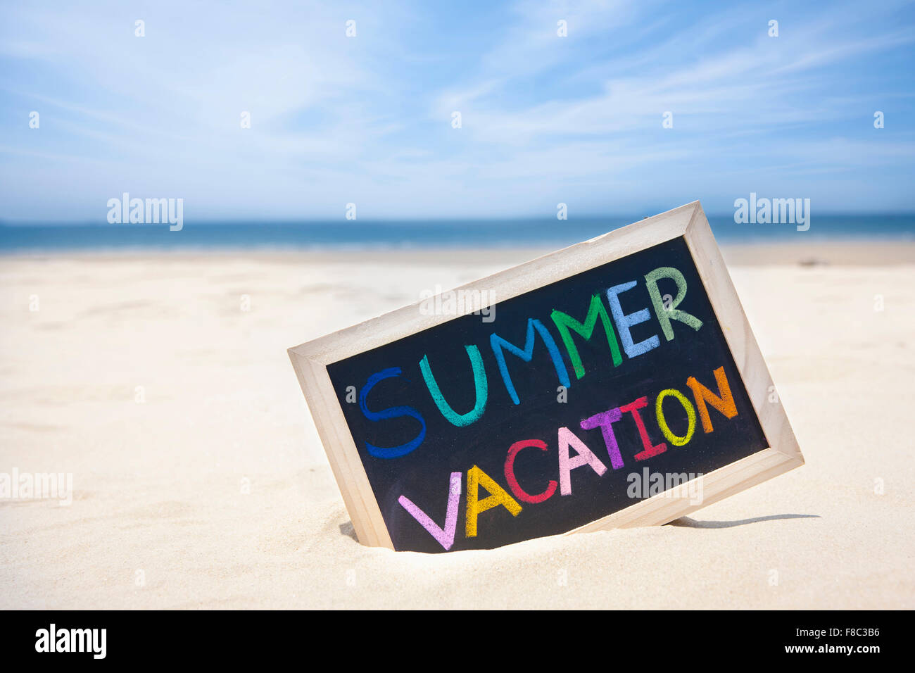 Word SUMMER VACATION written in wood frame with the background of beach ...