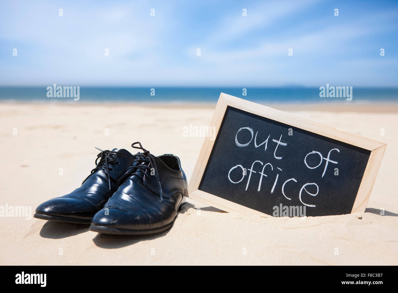 Pair of man's business shoes with Out of Office word written in wood ...