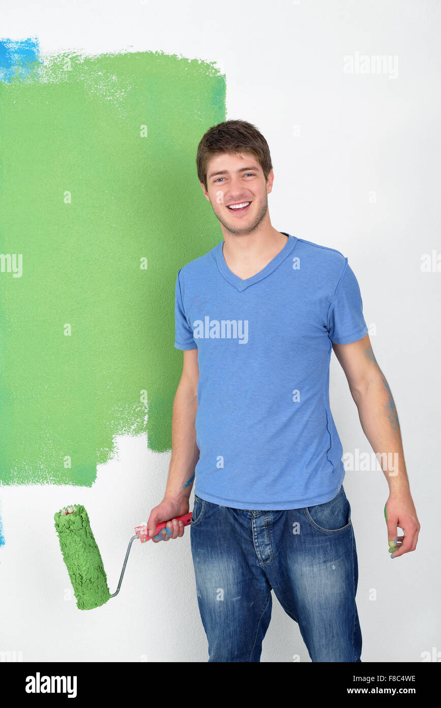 handsome young man paint in blue and green color white wall of new home ...