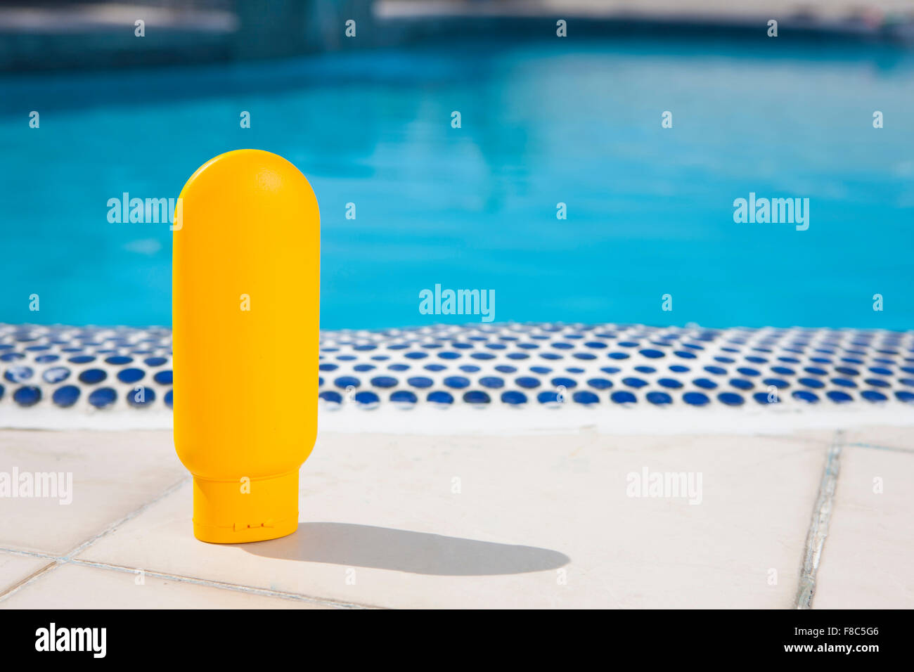 Sunscreen standing on tile floor with the background of swimming pool ...