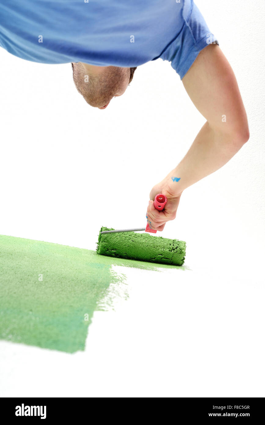 handsome young man paint in blue and green color white wall of new home ...
