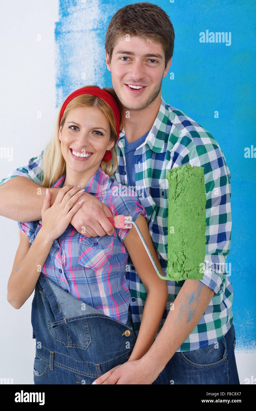 happy young couple paint in green and blue color white wall of their ...