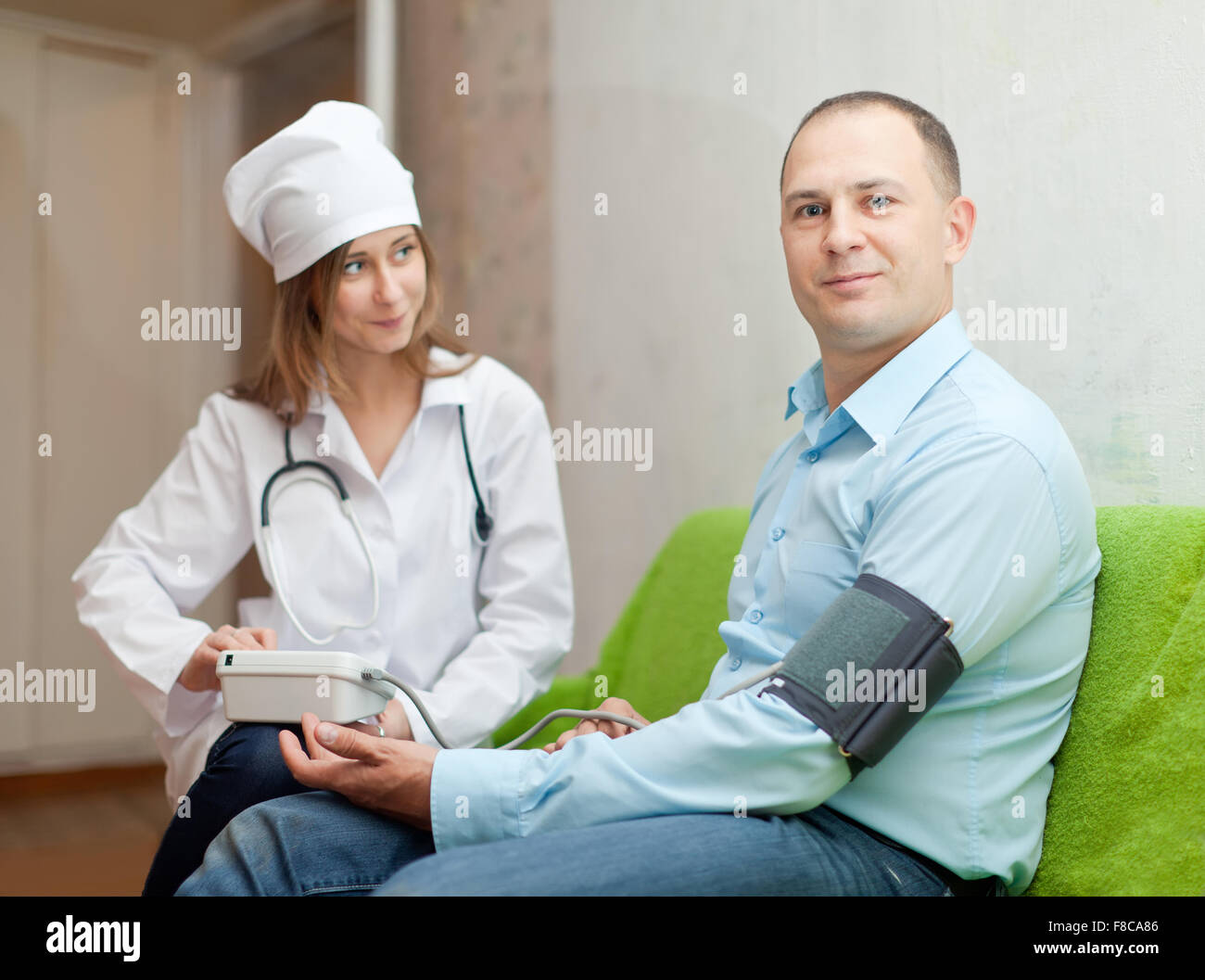 Woman doctor examining the patient on couch. Focus on man Stock Photo ...