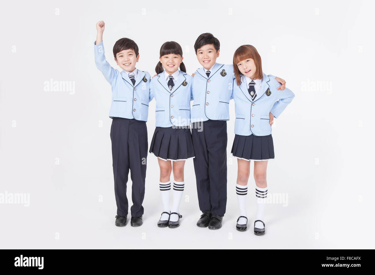 Four elementary school age kids standing together with their arms ...