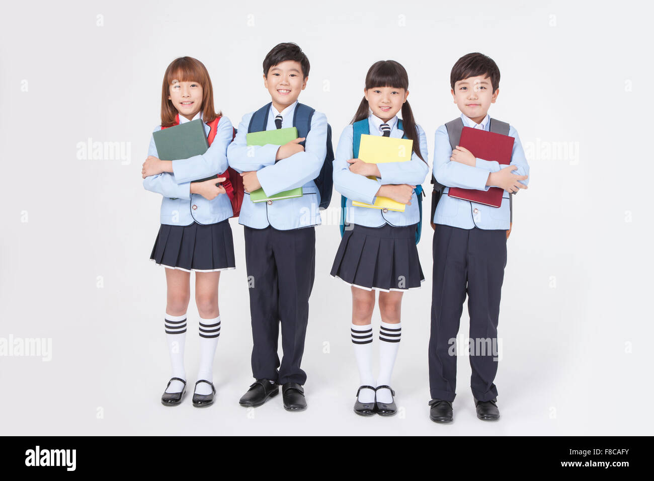 Four elementary students with backpack standing together and holding a ...