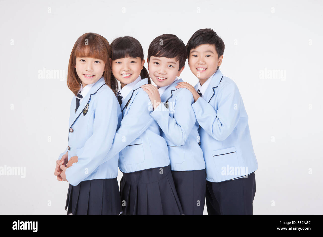 Four elementary students in school uniforms standing close to each ...