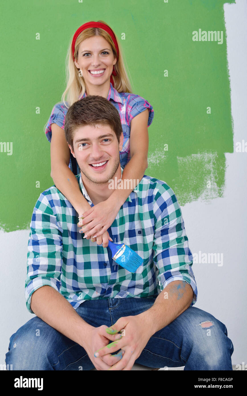 happy young couple paint in green and blue color white wall of their ...