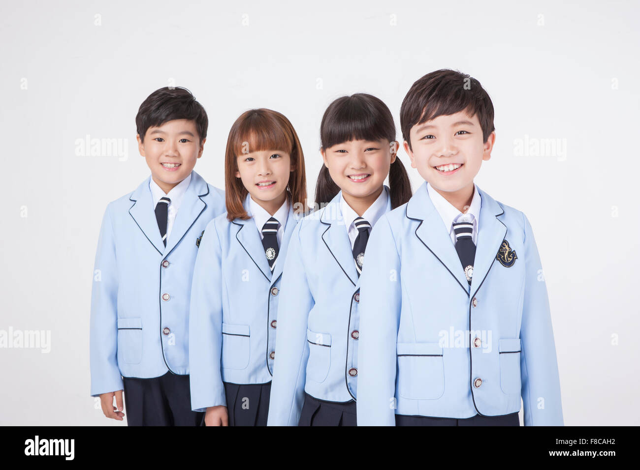 Four elementary students in school uniforms in line staring forward ...