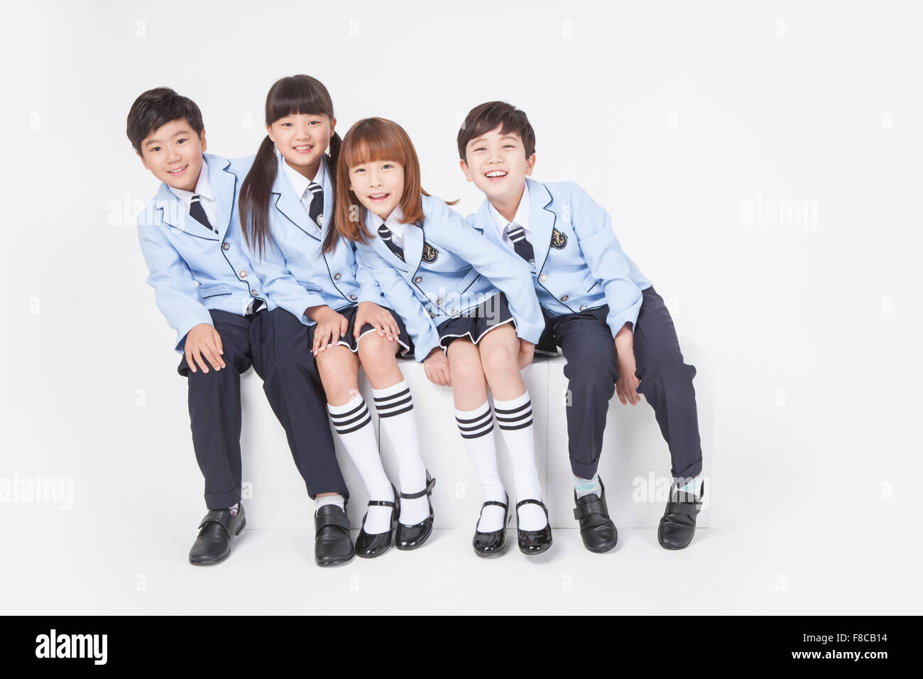 Four elementary students in school uniforms sitting together with their ...