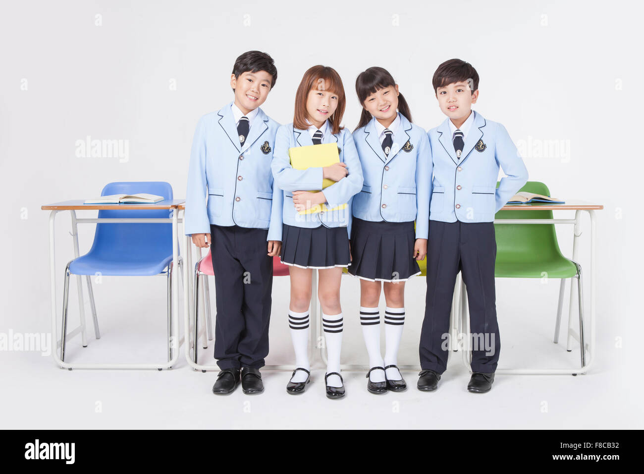 Four elementary students in school uniforms standing in front of their ...