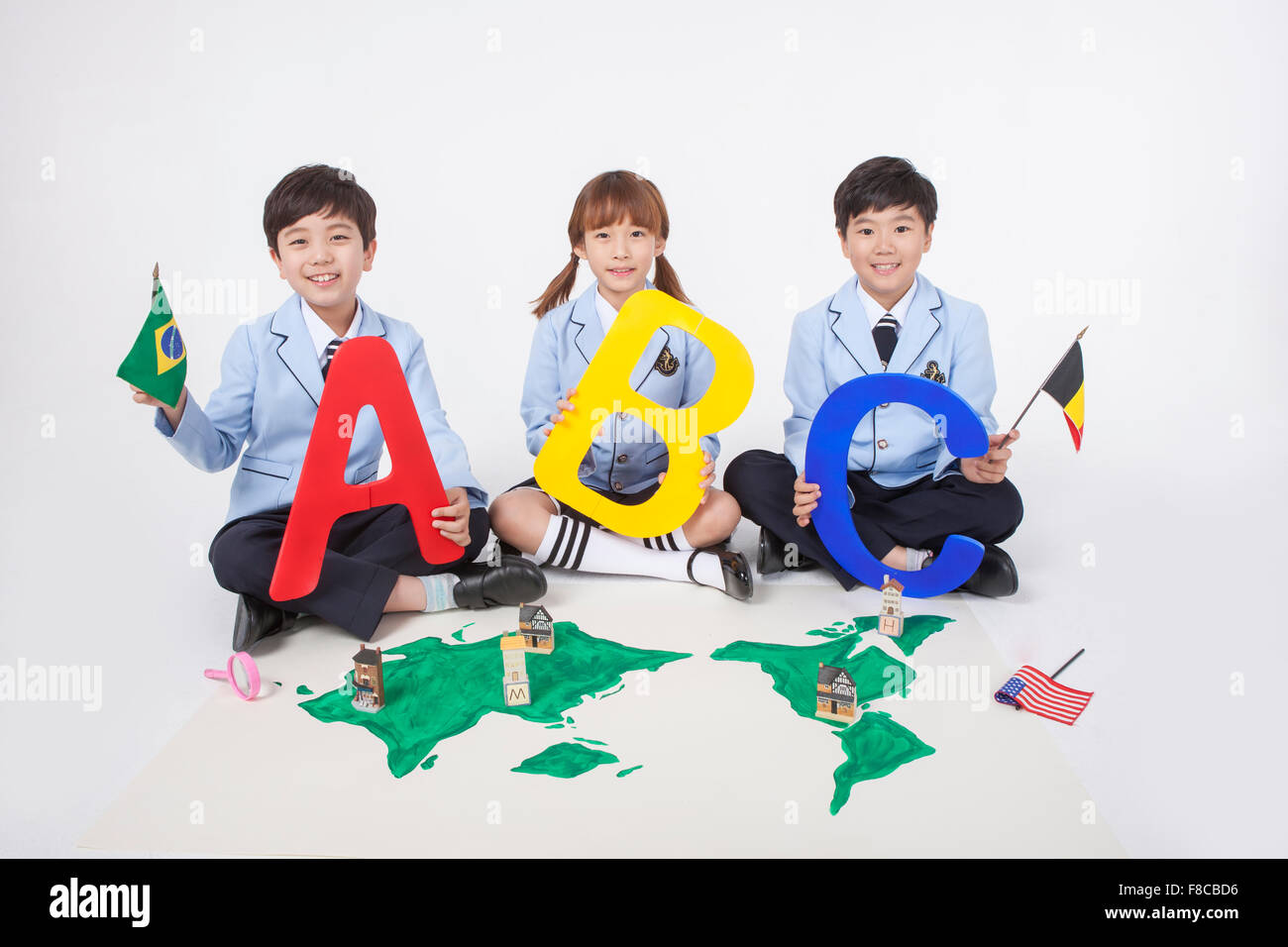 Three elementary school students in school uniforms sitting next to ...
