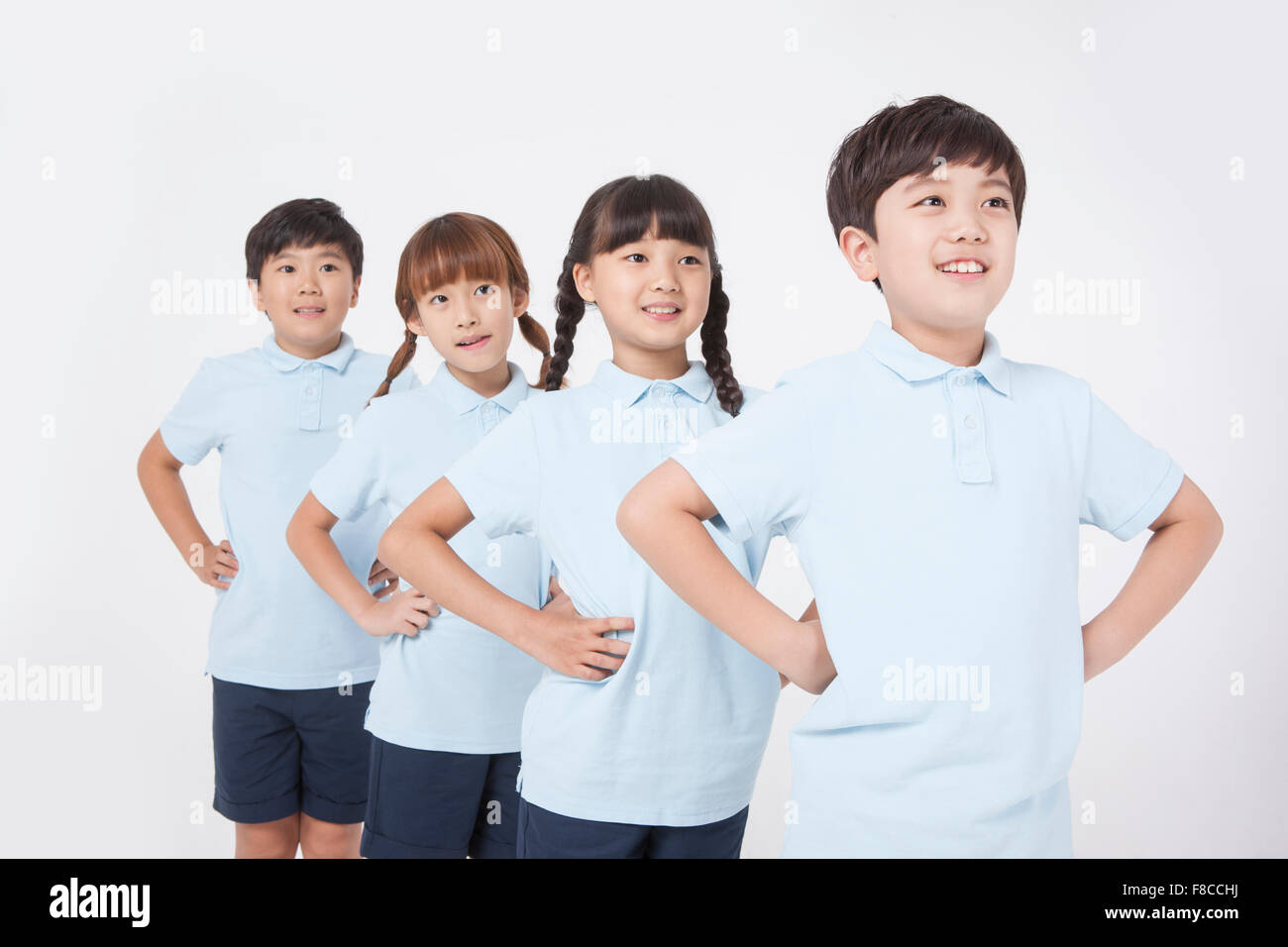 Four elementary students in sports uniforms standing in line with their ...