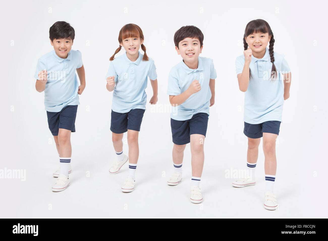 Four elementary school students in sports uniforms being about to run ...