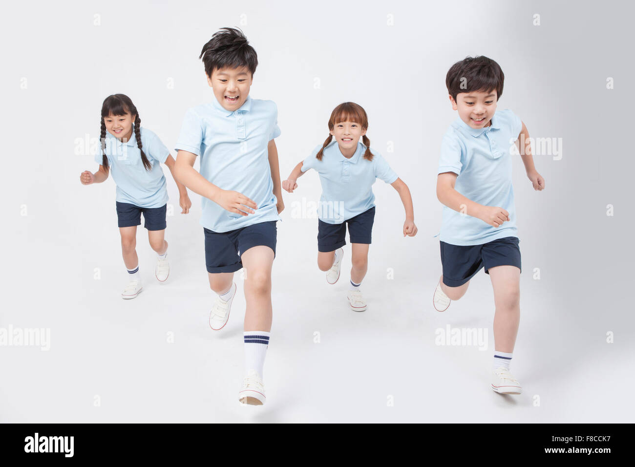 Four elementary school students in sports uniforms running Stock Photo ...