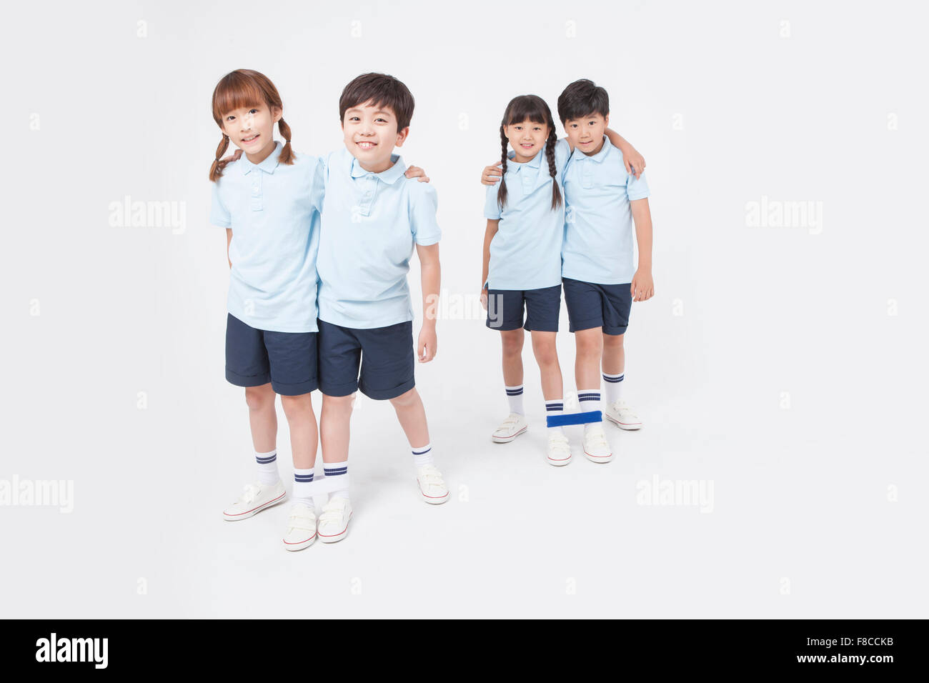Two pairs of elementary school students with their feet tied together ...