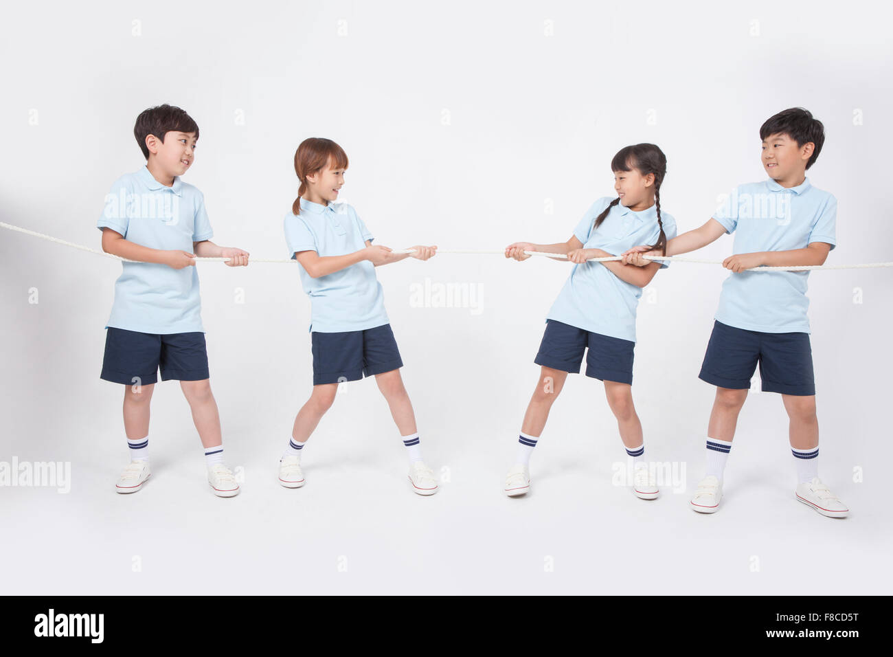 Two elementary school students in sports uniforms holding a rope and ...