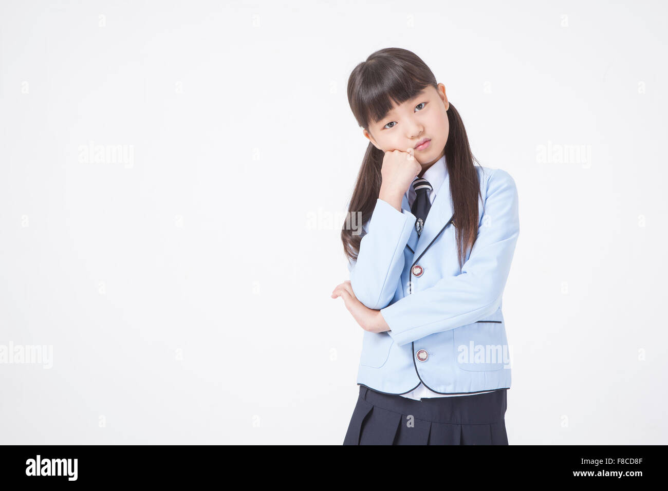 Elementary school girl in school uniforms resting her head in her hand ...