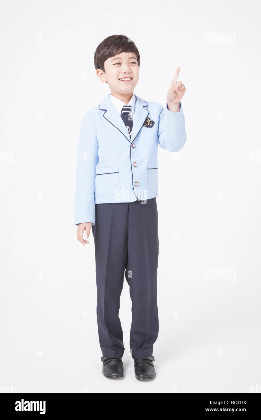 Elementary school boy in school uniforms standing and pointing up with ...