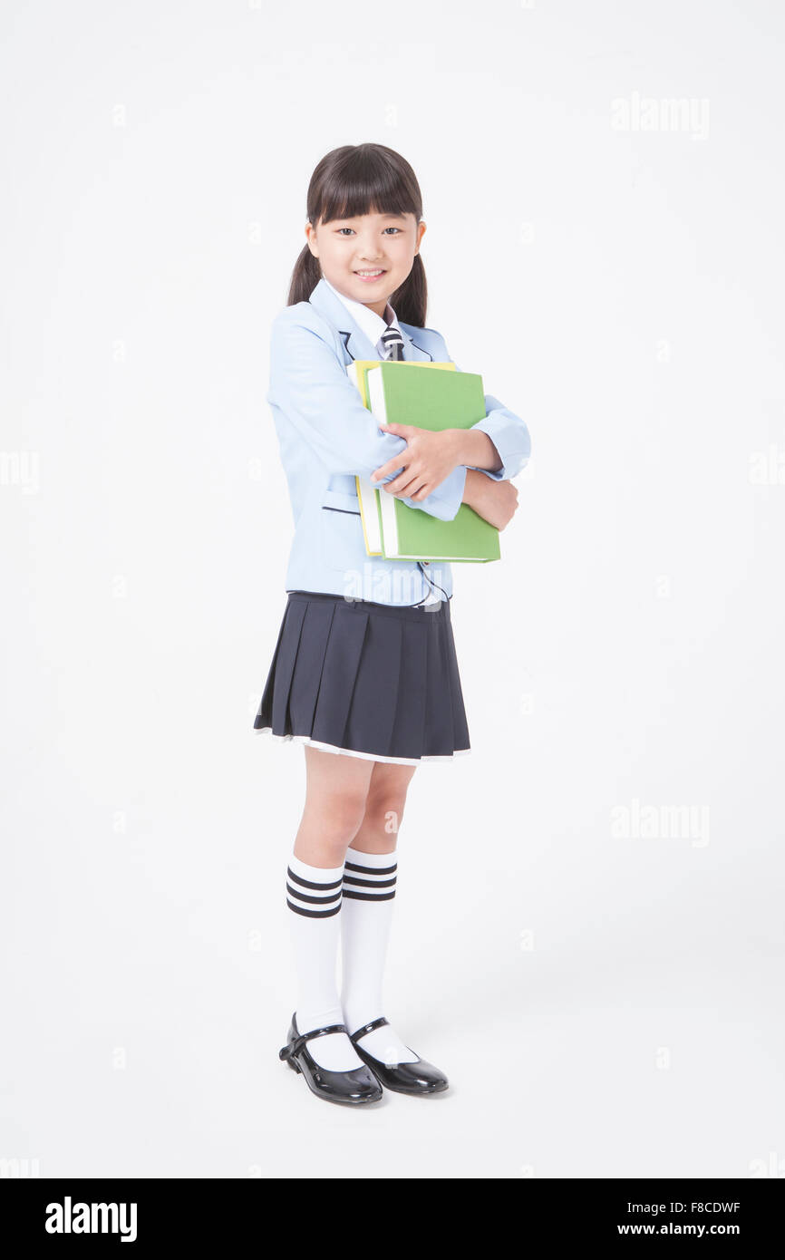 Elementary school girl in school uniforms holding books in her arms and ...