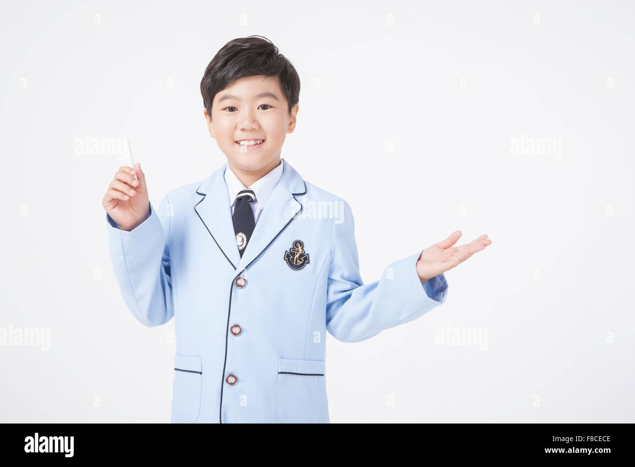Elementary school boy in school uniforms holding a chalk and gesturing ...