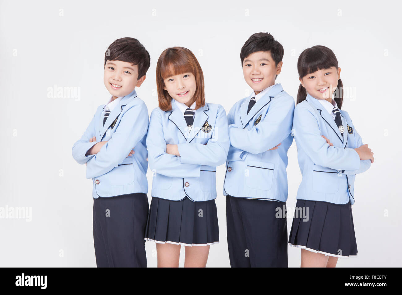 Four elementary school students in school uniforms together with their ...